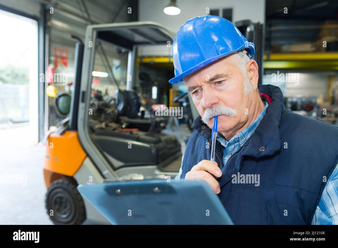 senior worker with forklift in warehouse in logistic area Stock Photo ...