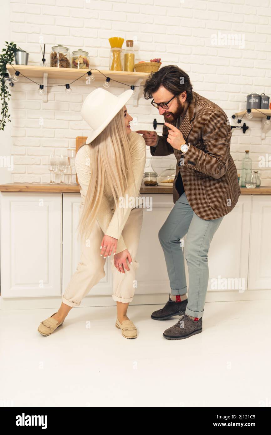Young Caucasian married people dancing in the kitchen looking at each ...