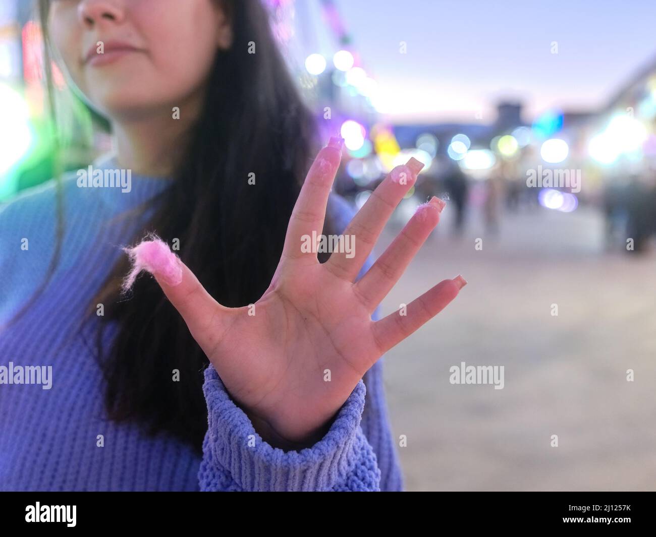 Woman showing palm of hand with traces of cotton candy stuck to it in a ...