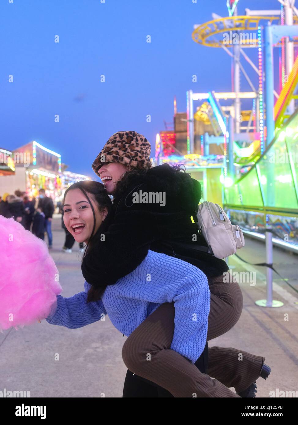 Woman carrying other woman while holding a cottn candy in a fair Stock ...