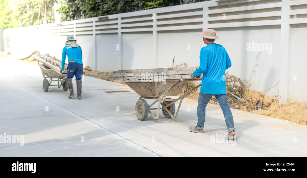 Two workers man pulling the cement cart for mixing the cement for ...