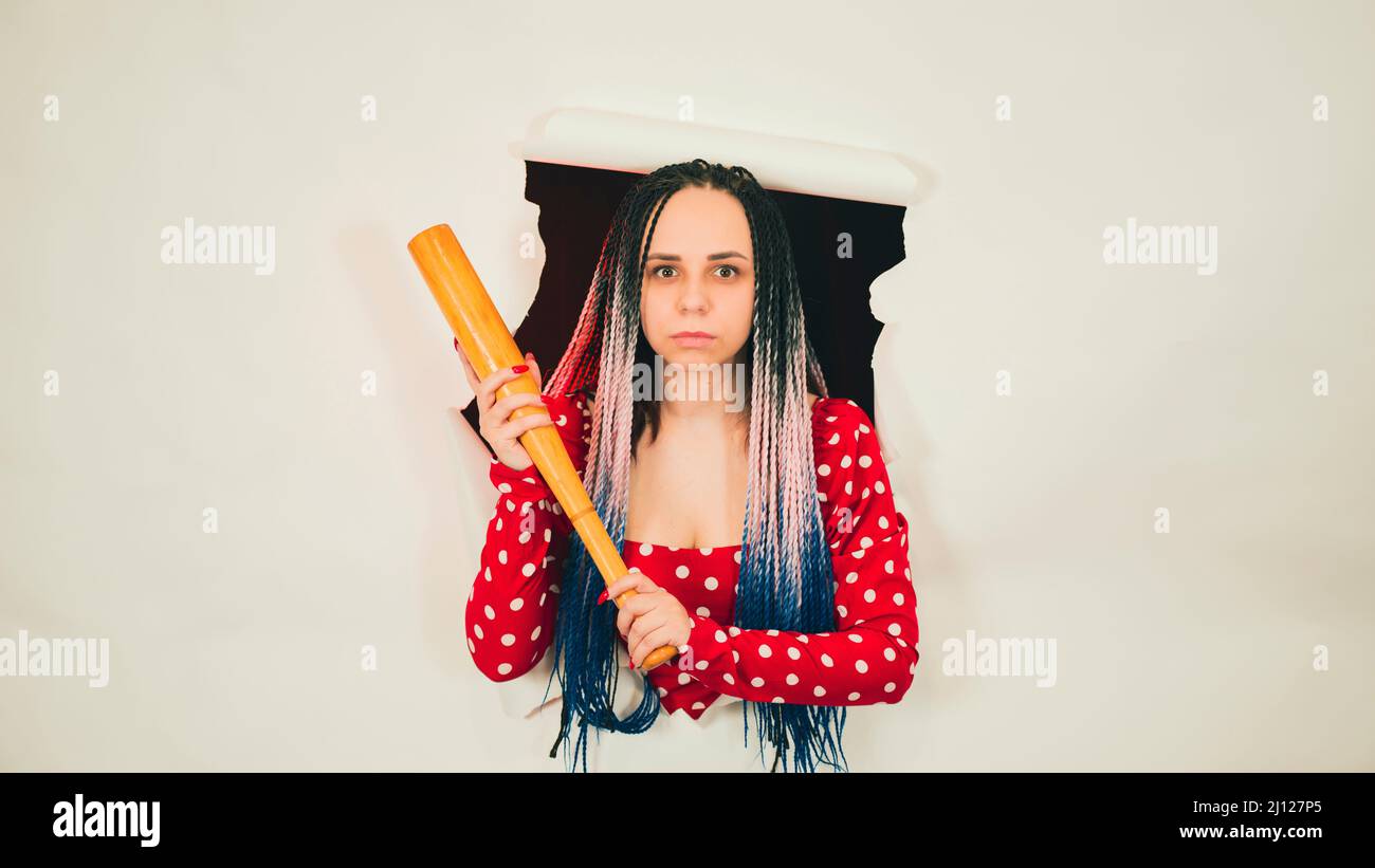 Young woman with baseball bat in hole of white background. Pretty lady ...