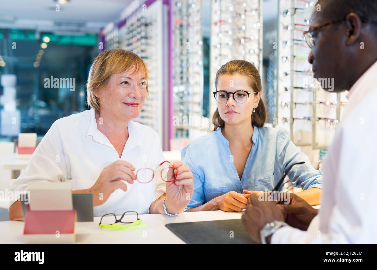 Male and female opticians helping client to choose a spectacles Stock ...