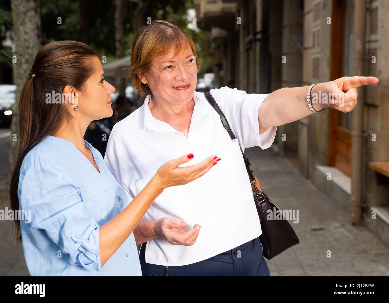 Elderly woman pointing direction to young female Stock Photo - Alamy