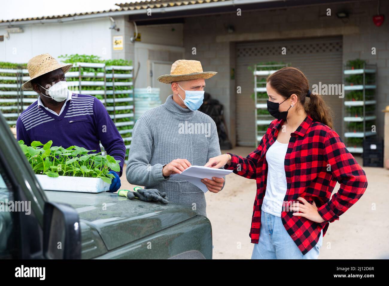 Female gardener in protective mask discussing contract with ...