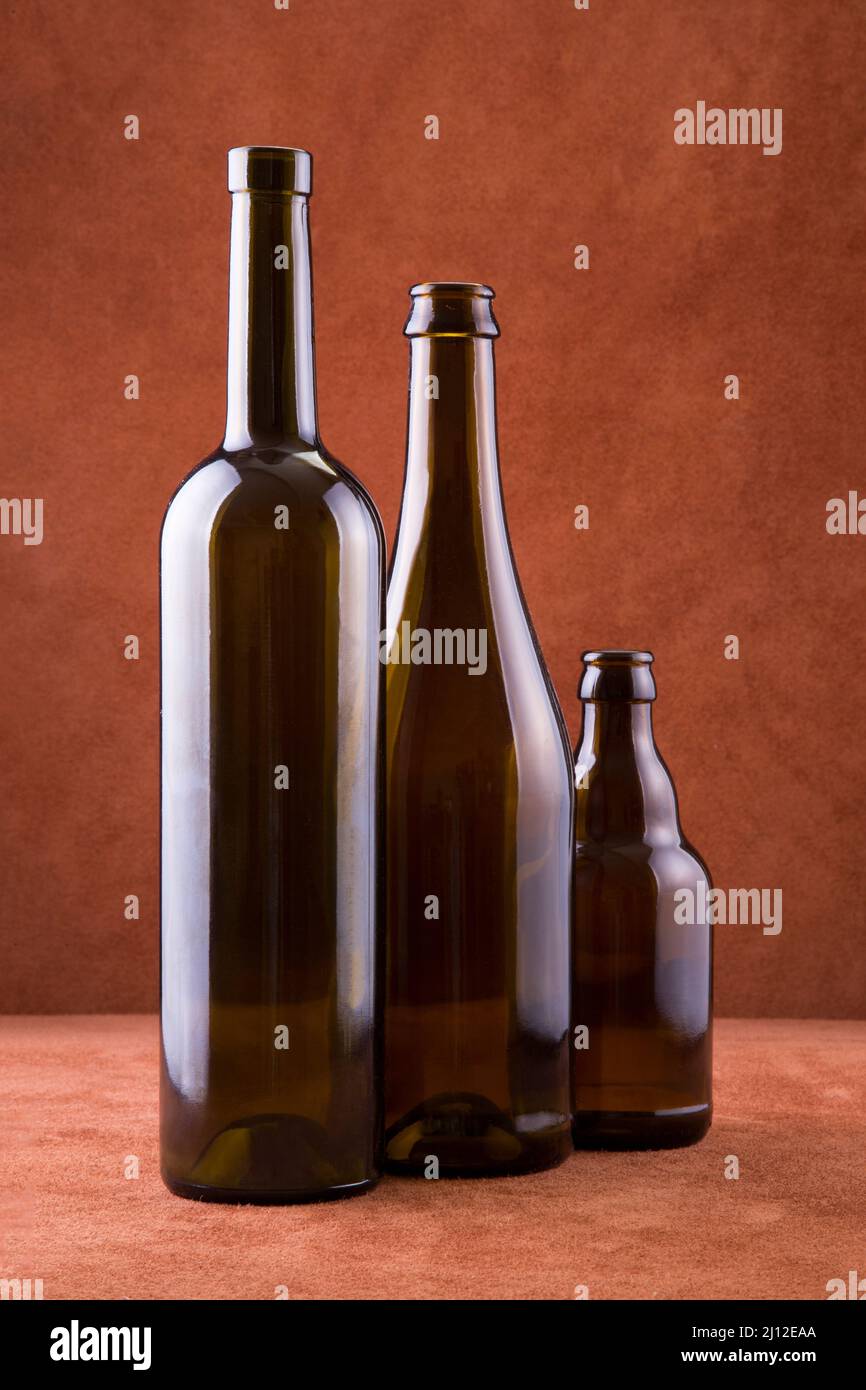 Still life with three glass bottles on a brown background Stock Photo - Alamy