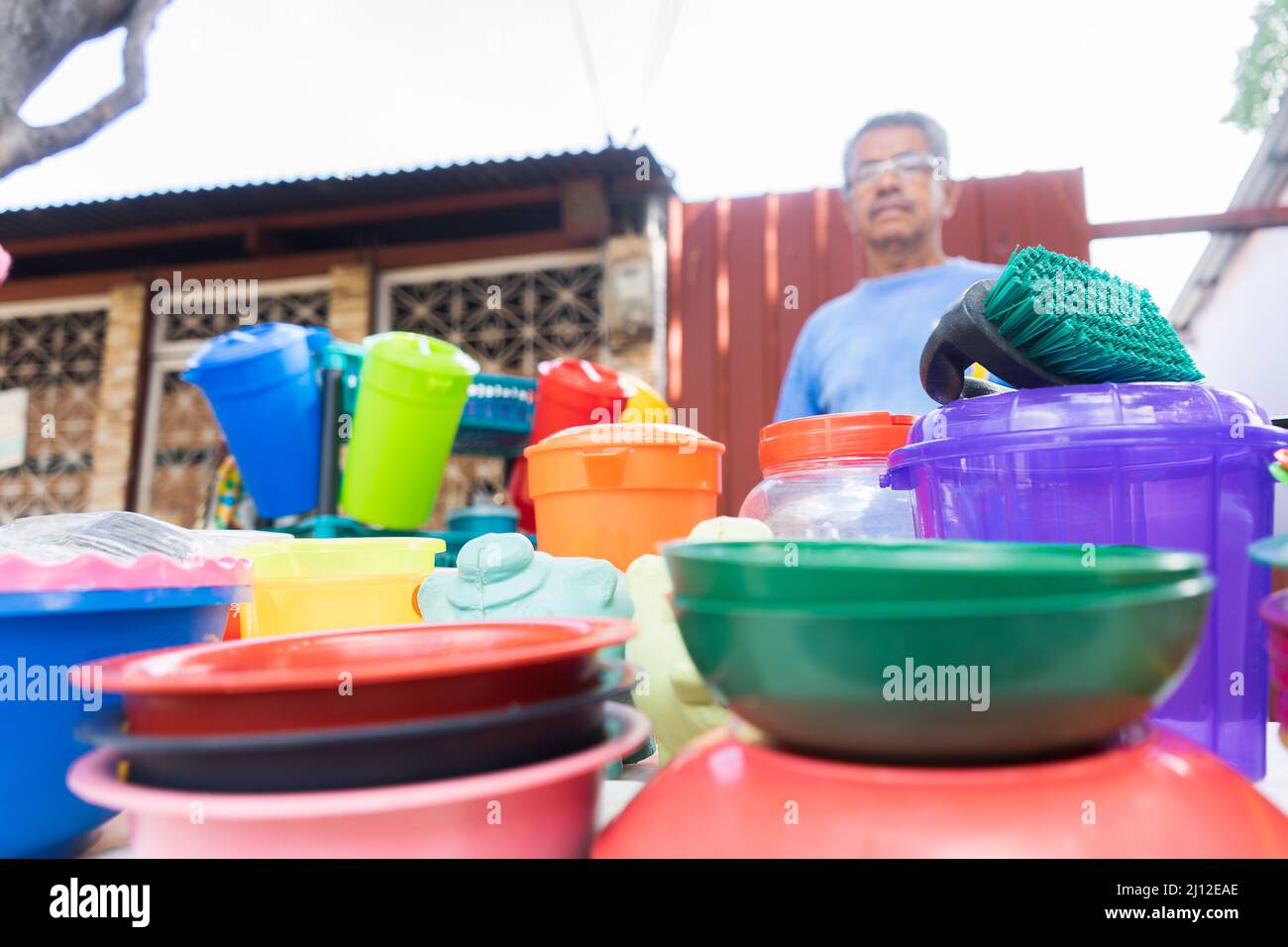 Latin adult man attends to his retail business selling plastic items on ...