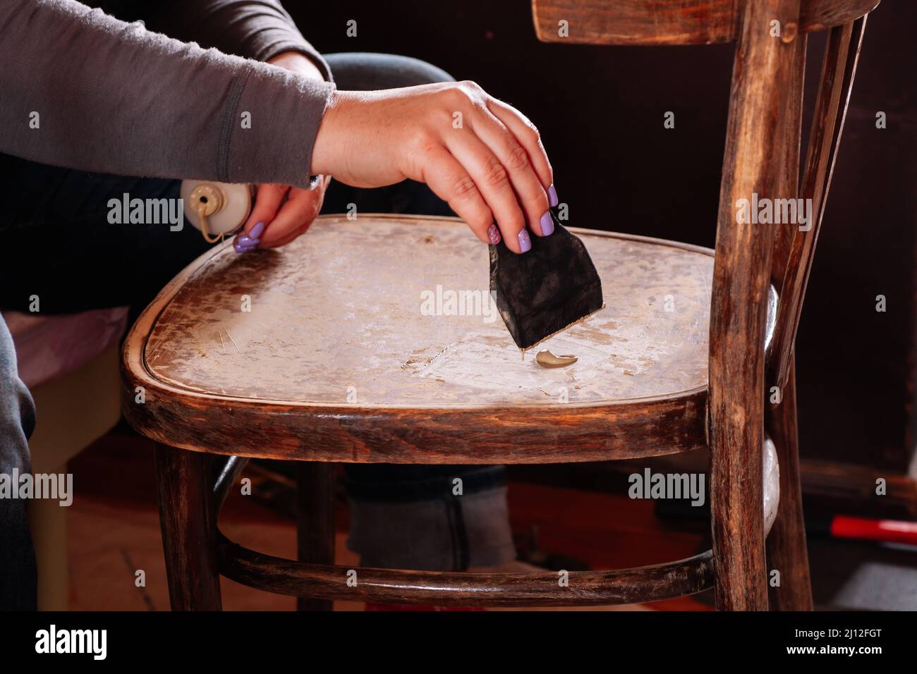 Closeup of hands spackling and leveling old stool surface getting ...
