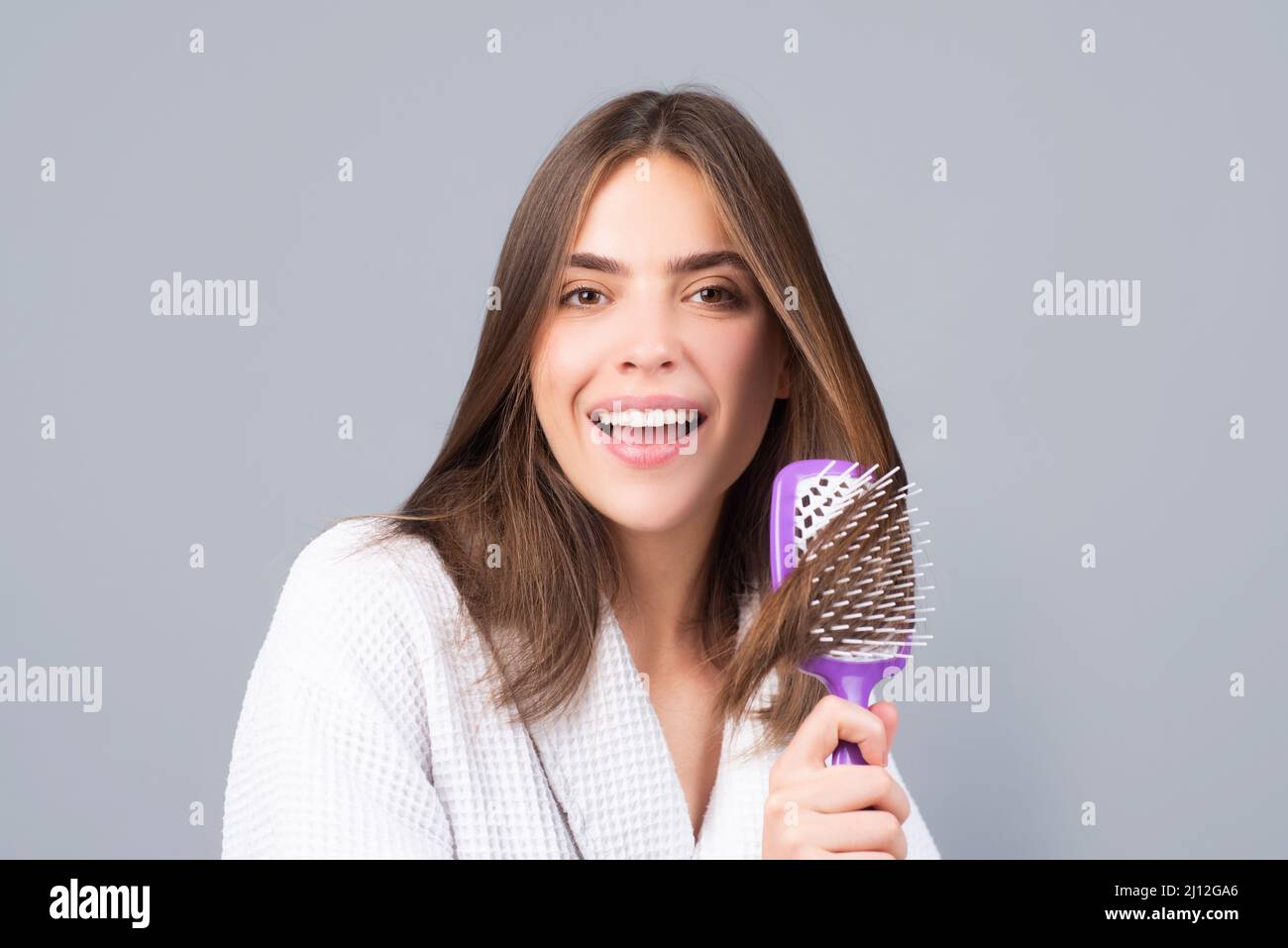 Happy smiling young woman combing hair. Portrait of female model with a ...