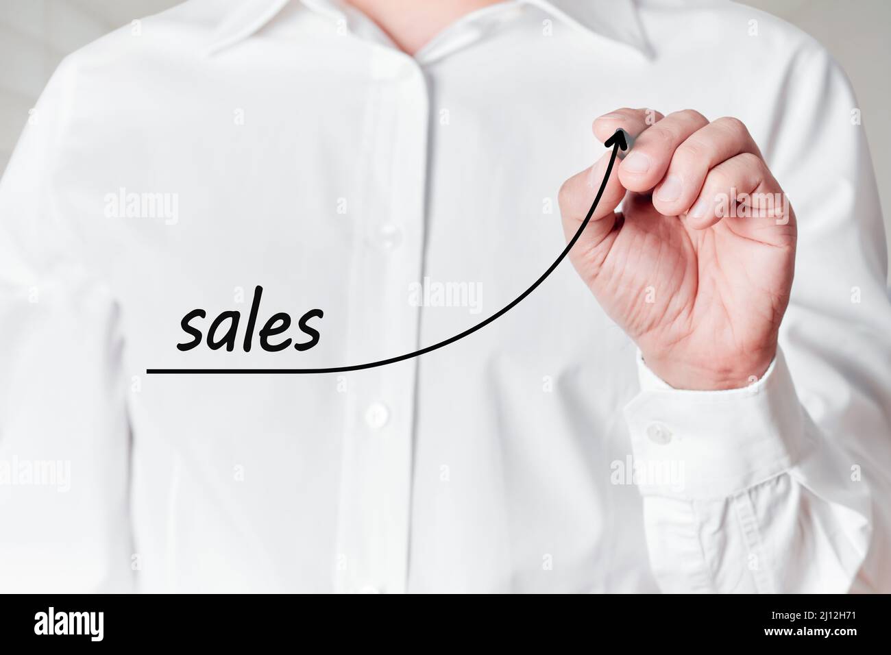 Businessman with pen draws a rising line graph with the word sales on a ...