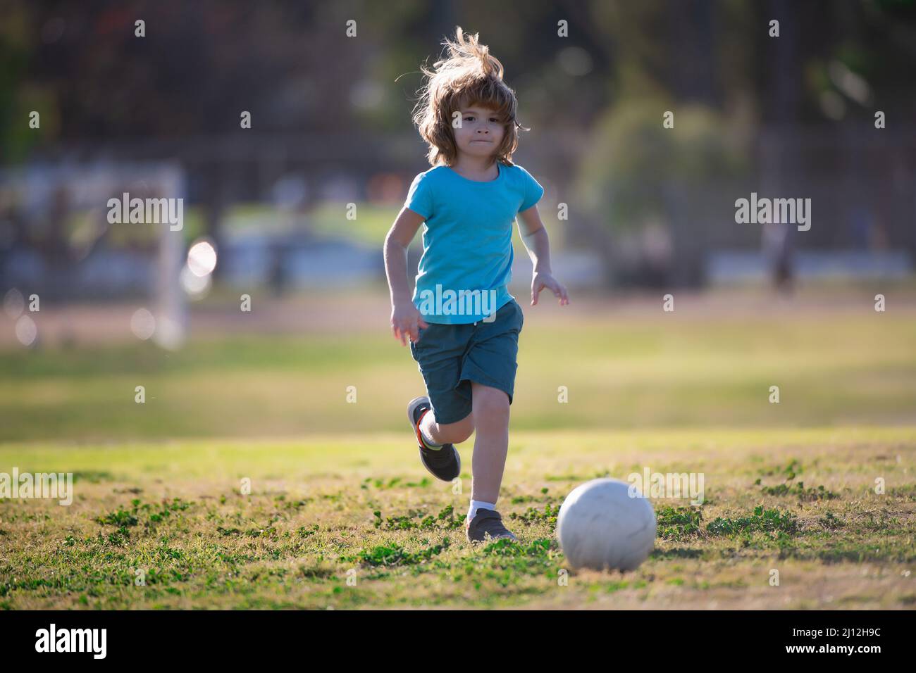 Boy child playing football on football field. Kid playing soccer ...