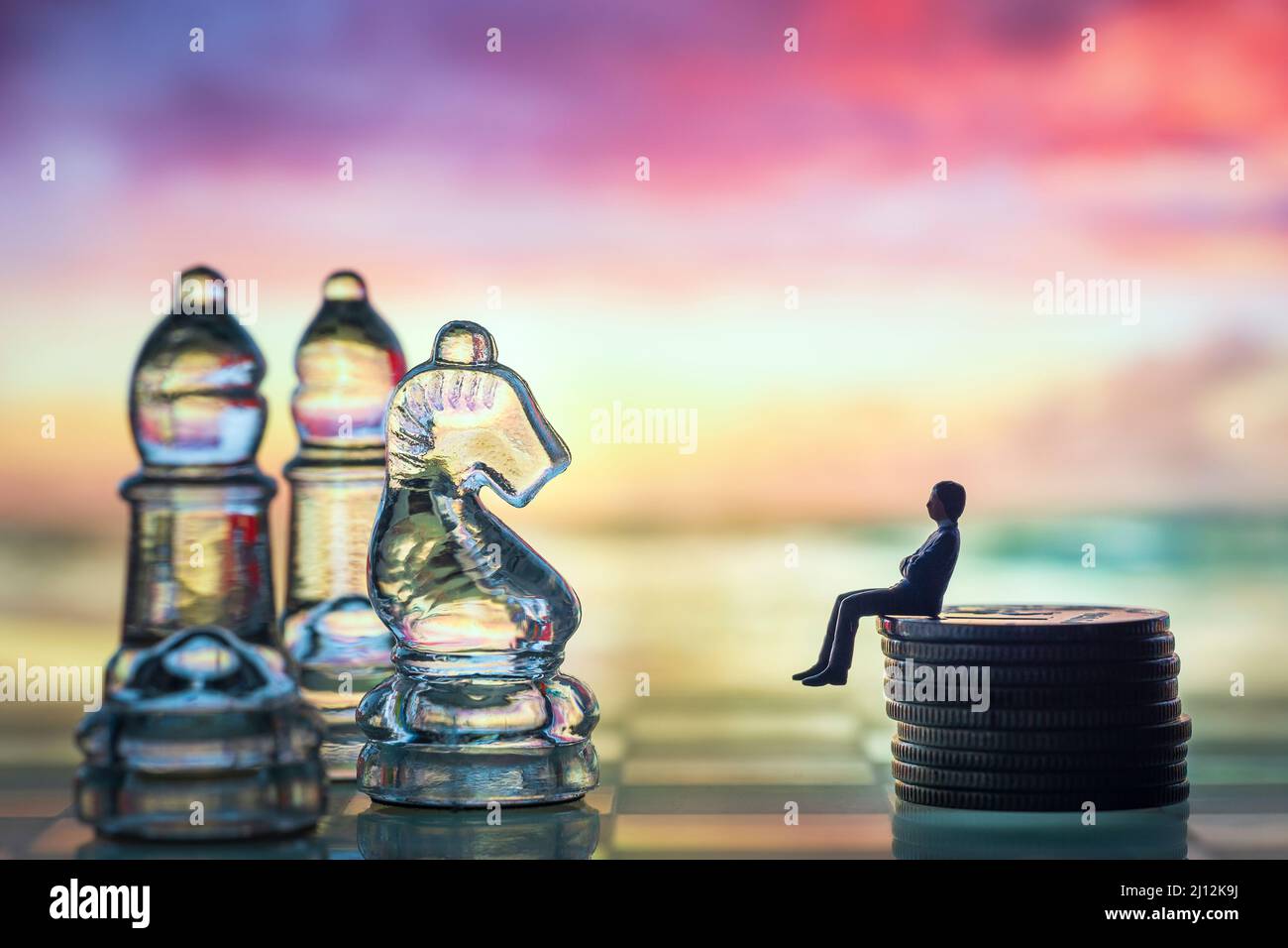 Miniature figure people as man sitting on stack of coins face to face ...