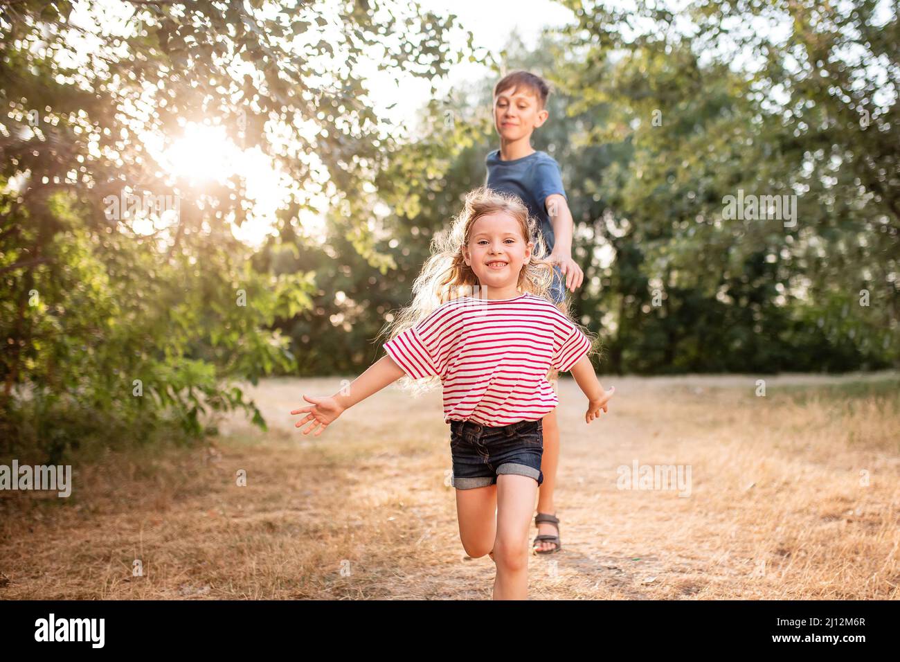 Happy children boy and girl frolic in the Park. The older brother plays ...