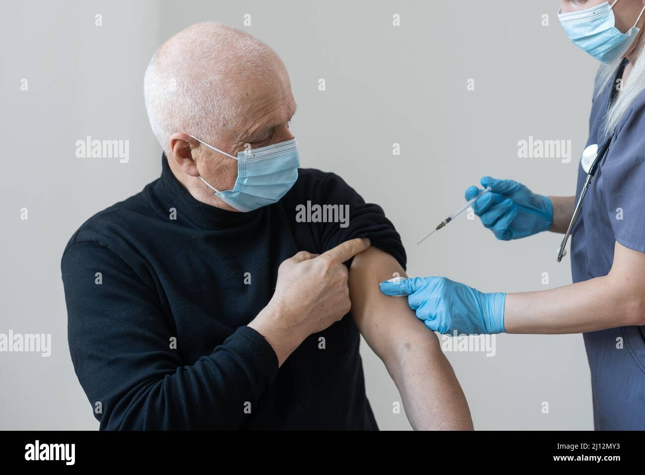 Doctor making injection to senior patient in clinic Stock Photo - Alamy