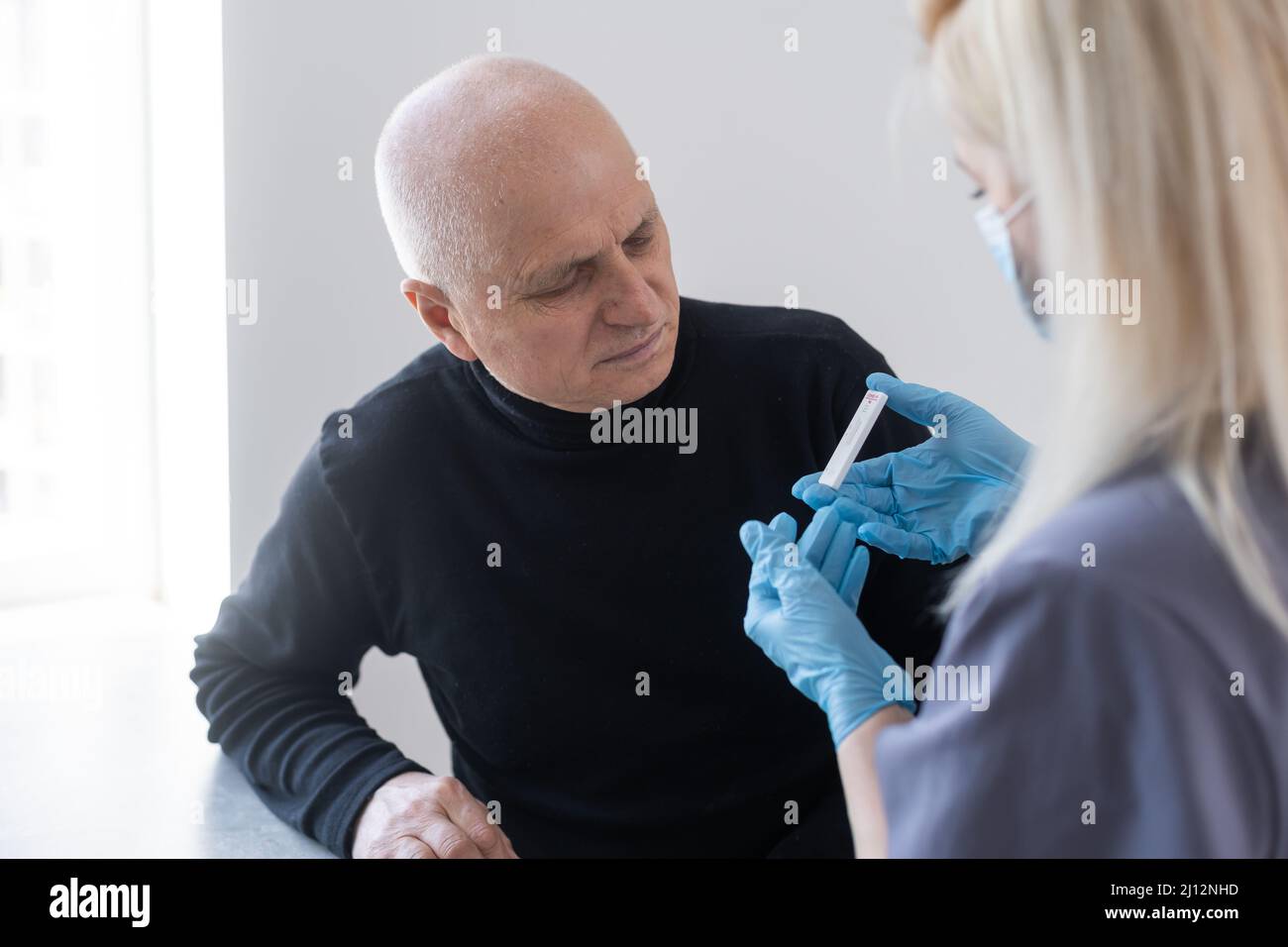 Nurse performing a coronavirus pcr test on an elderly man in his home ...