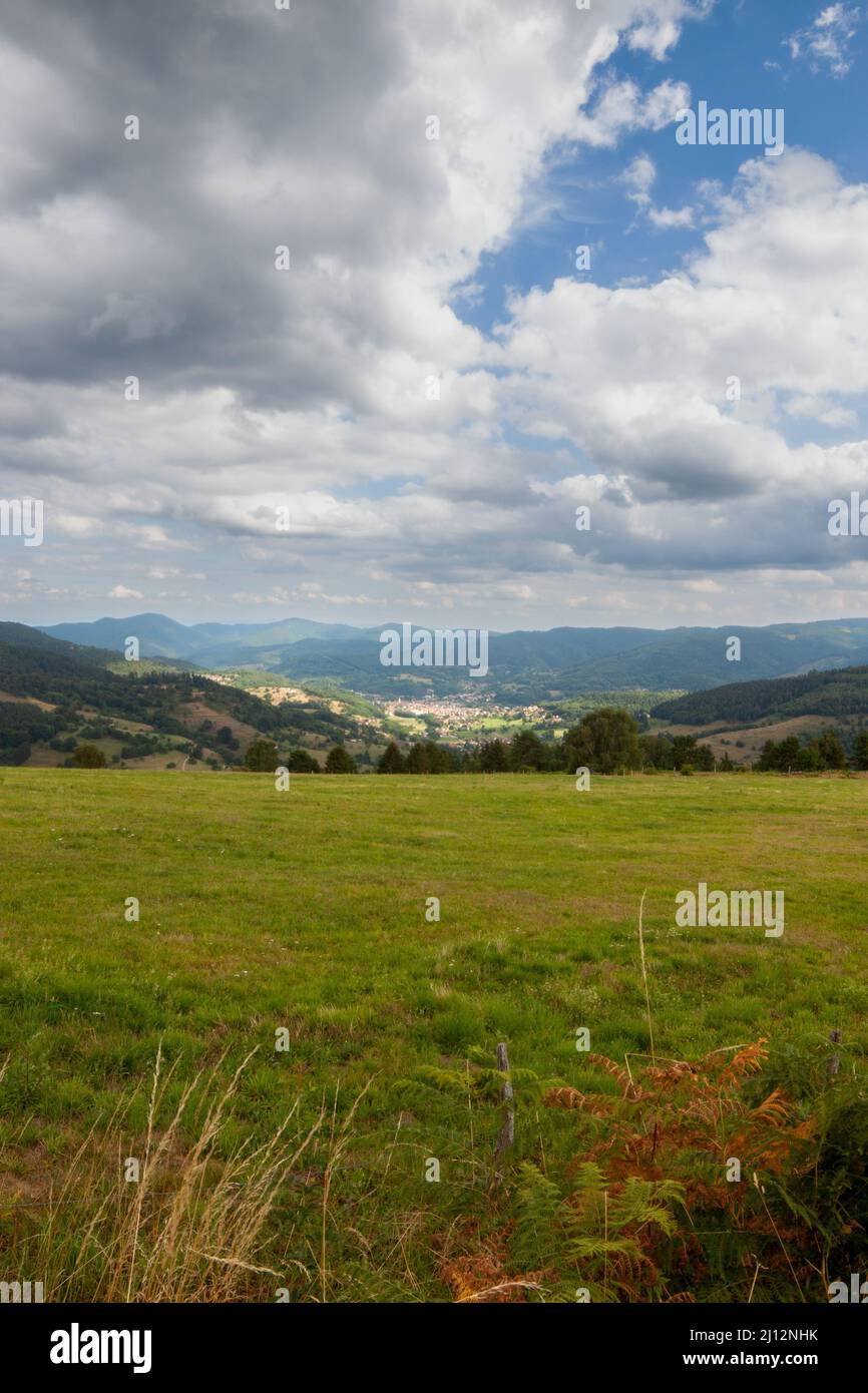 The sky is overcast and a little blue. A large green meadow slopes down ...