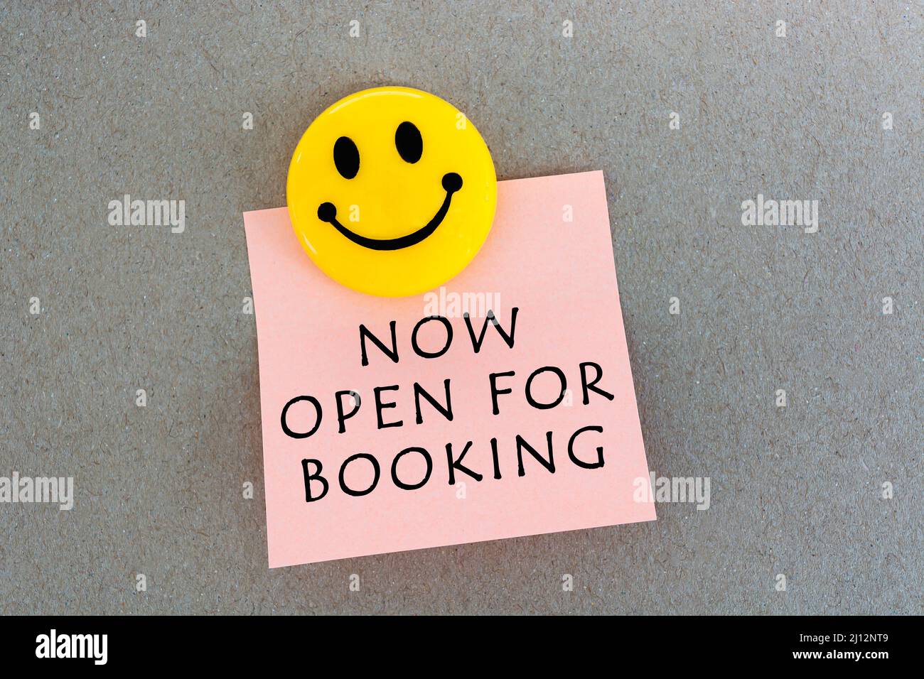 Now open for booking text on sticky notes with yellow smile face magnet ...