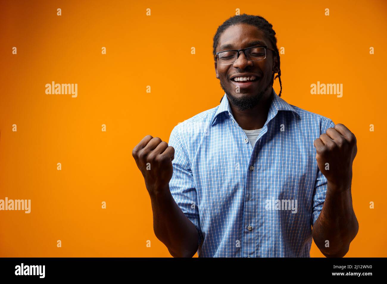 Portrait of overjoyed black man celebrating success with clenched fists ...