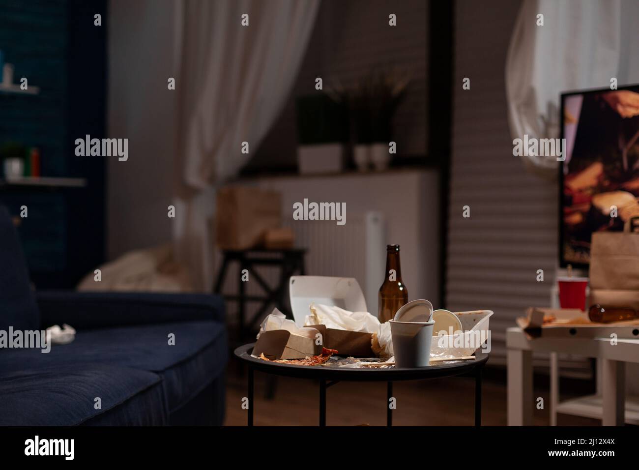 Nobody in living room with messy rubbish cans and leftovers food on ...