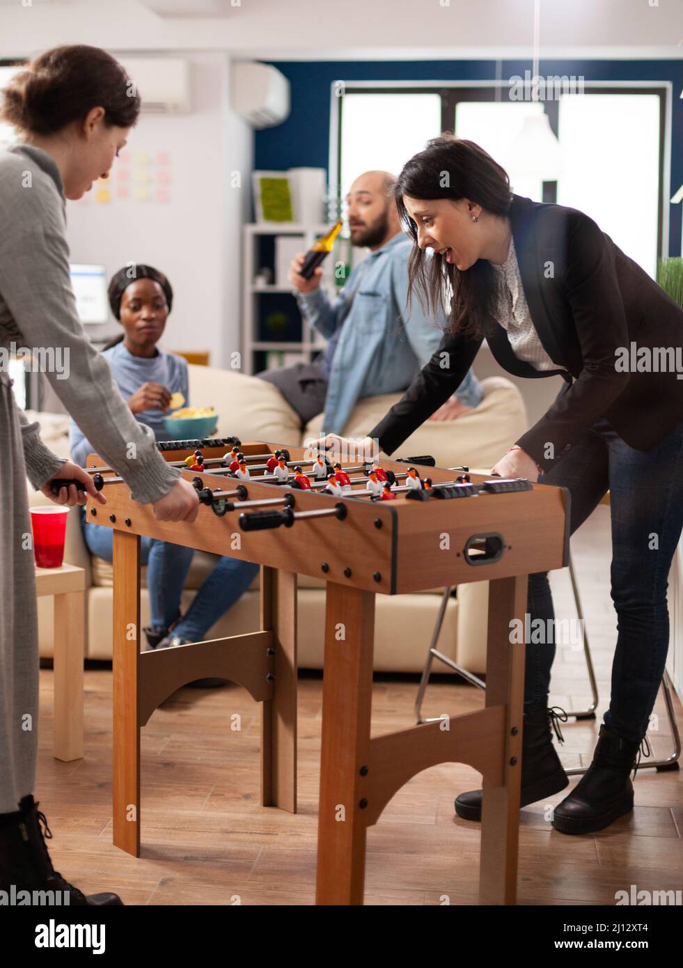 Multiethnic group of people playing at foosball game table, enjoying ...