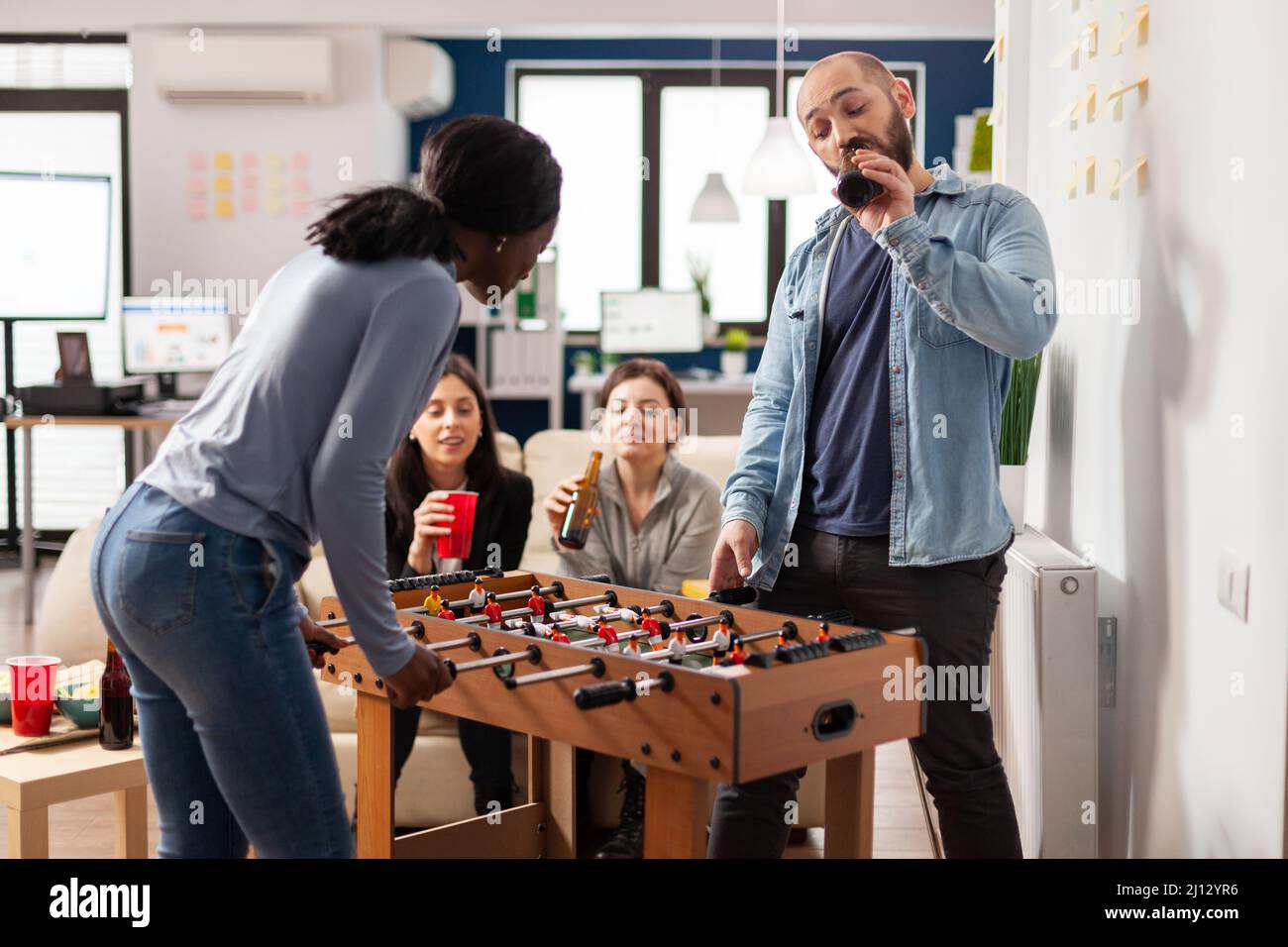 Multiethnic group of people playing at foosball table game, meeting for ...