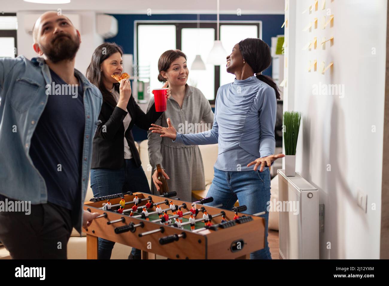 Cheerful people having fun with foosball table game at after work ...
