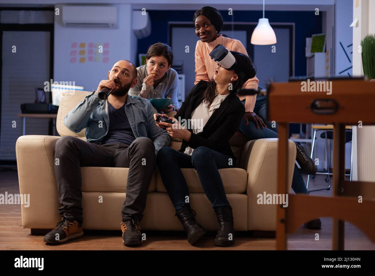 Office colleagues using vr headset and joystick to play videogames at ...