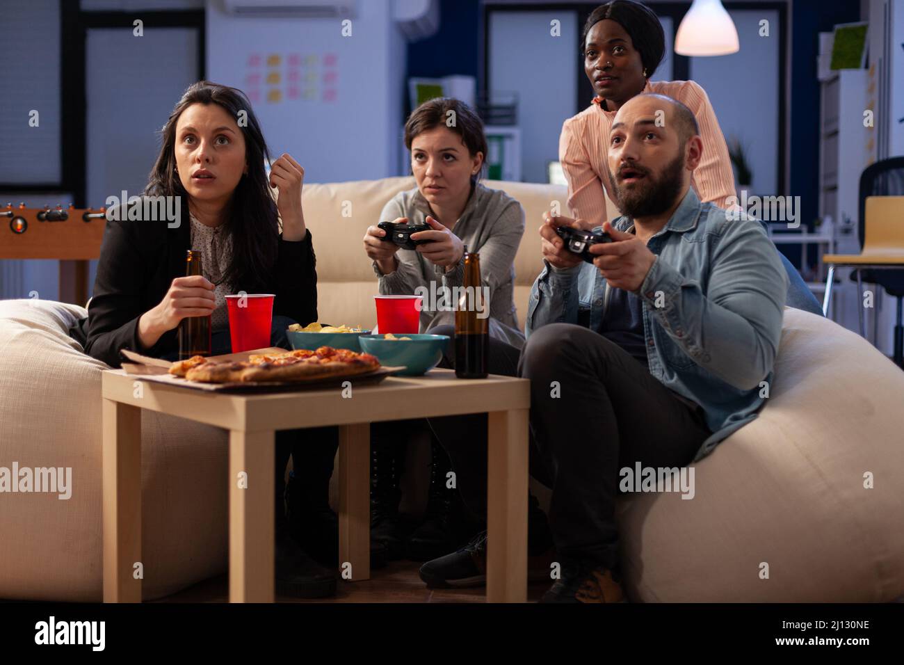 Office colleagues enjoying video games play with joystick on tv console ...