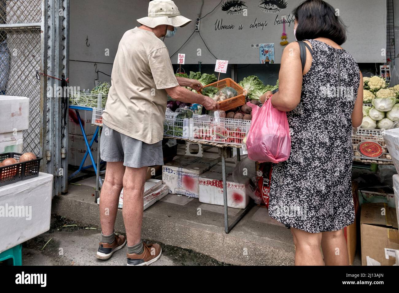 Woman shopping vegetables and buying green groceries from a male shop ...