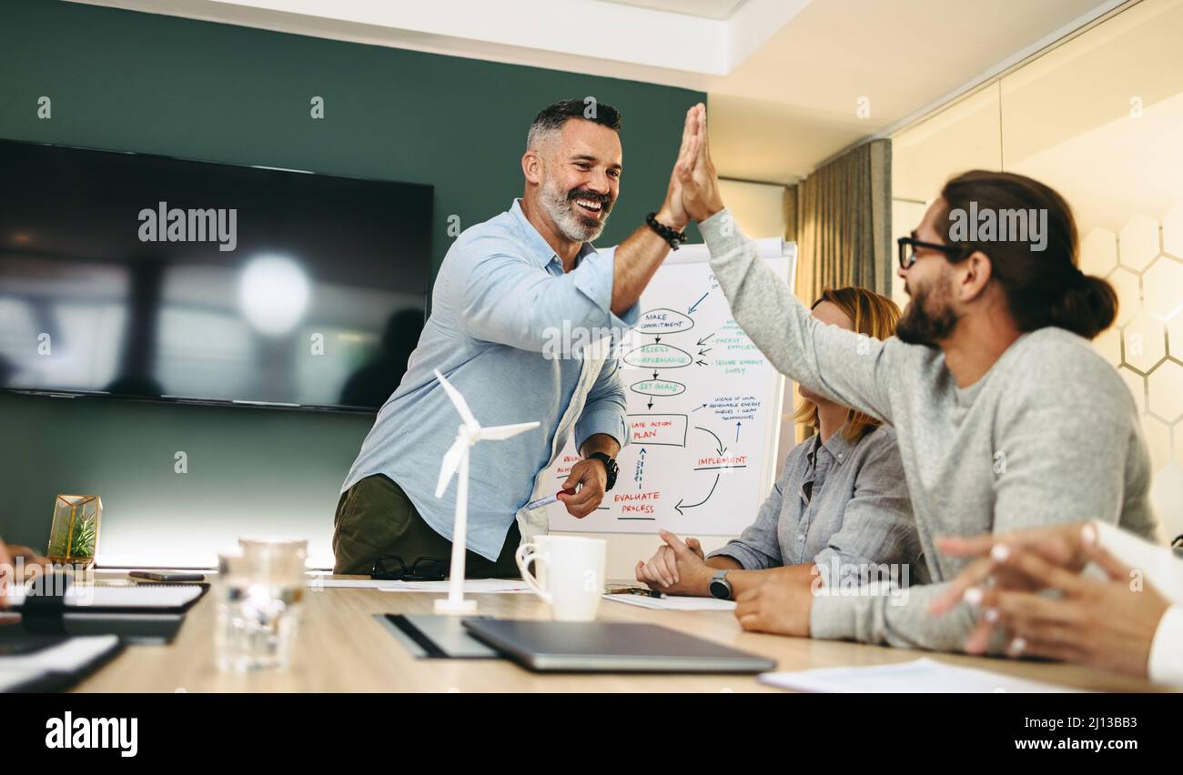 Successful businessmen high fiving each other during a meeting in a ...