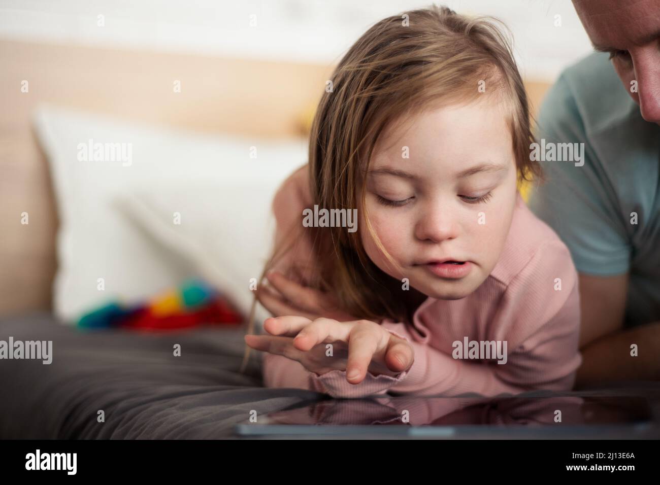 Father and his little daughter with Down syndrome lying on bed and ...
