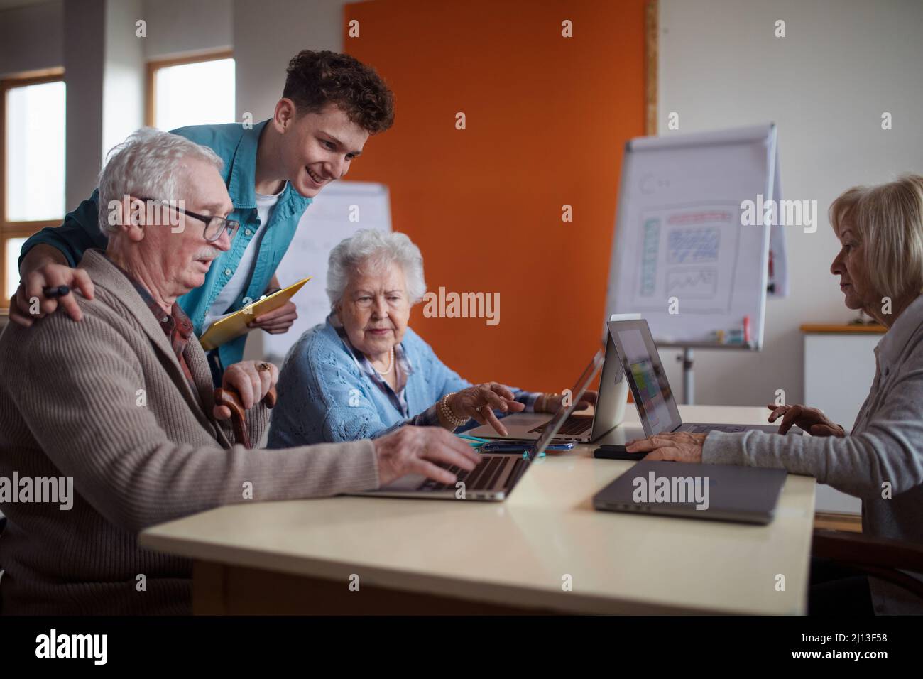 Senior group in retirement home with young instructor learning together ...