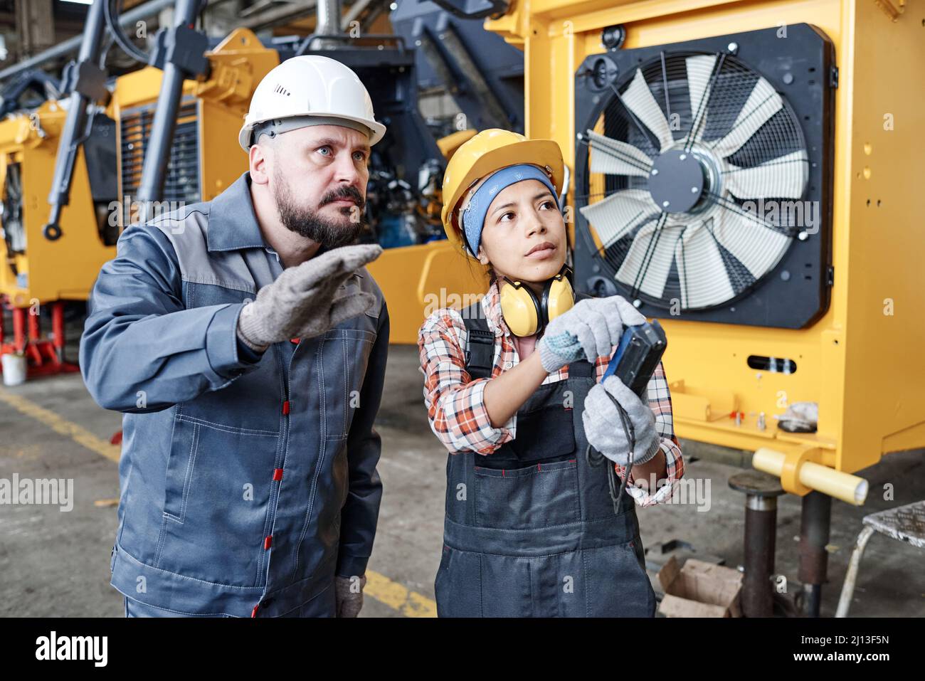 Young female engineer pressing button on remote control while her male ...
