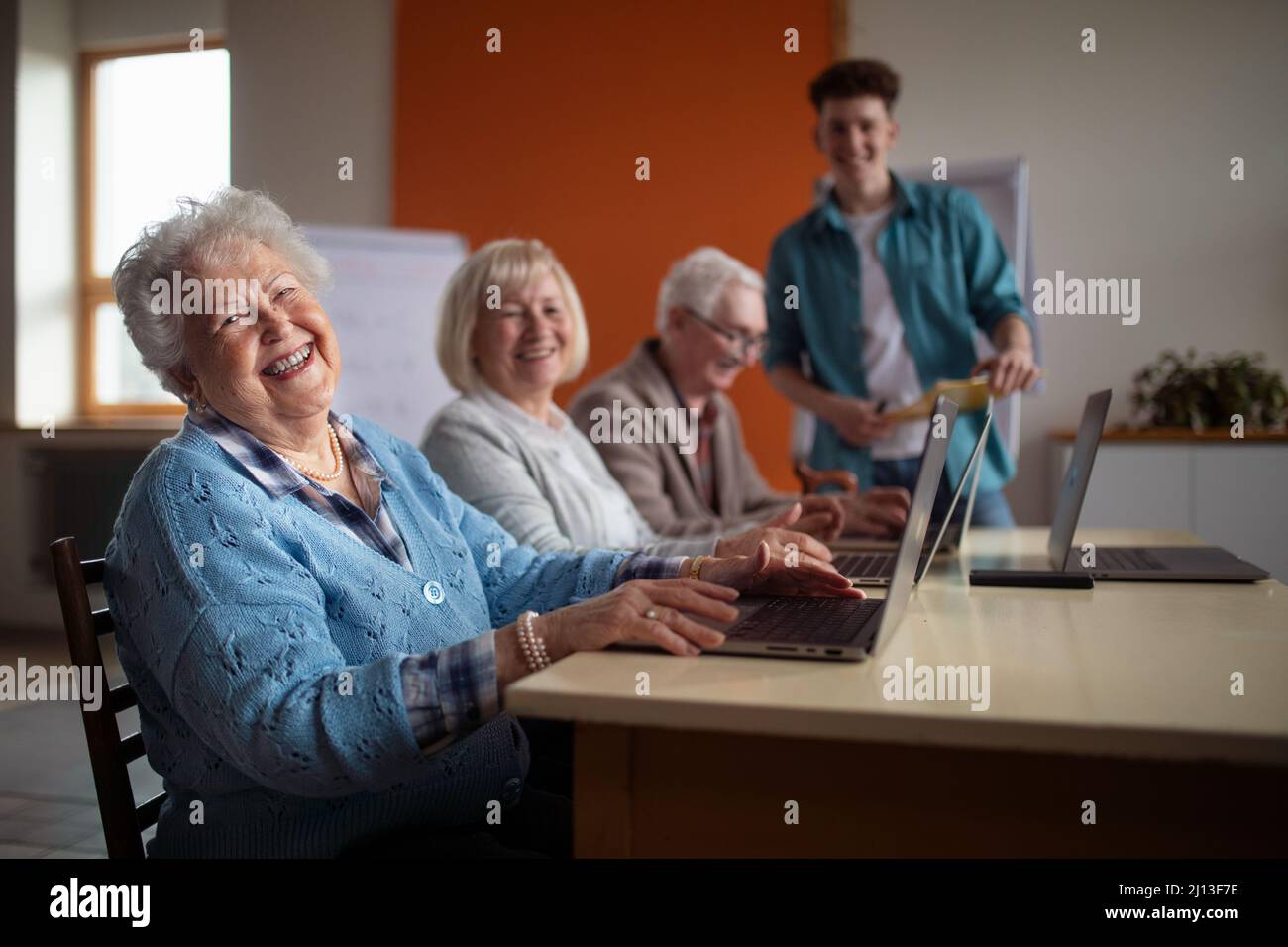 Senior group in retirement home with young instructor learning together ...