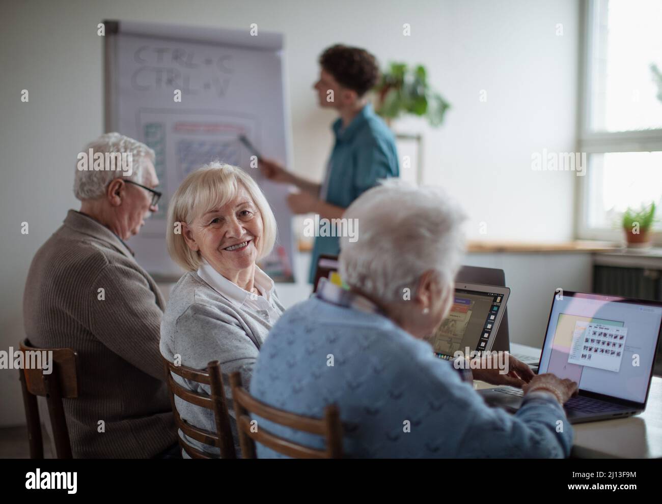 Senior group in retirement home with young instructor learning together ...