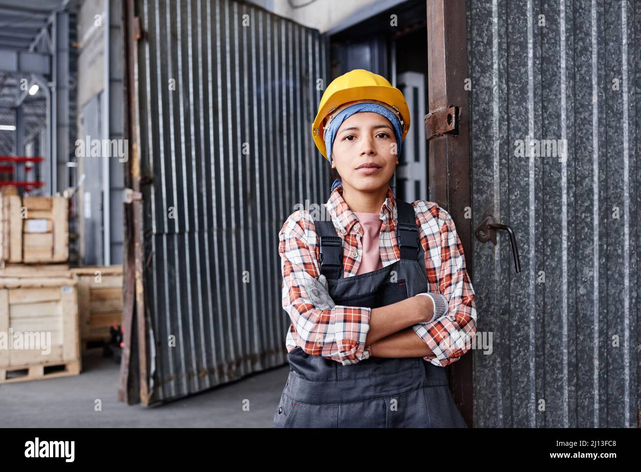 Young confident Hispanic female engineer in coveralls and protective ...