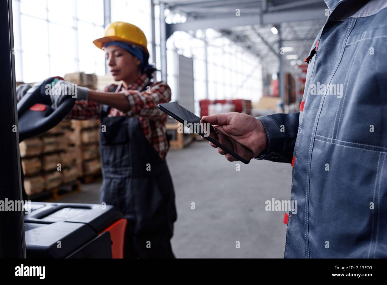 Hand of male manager of quality control in workwear holding tablet ...
