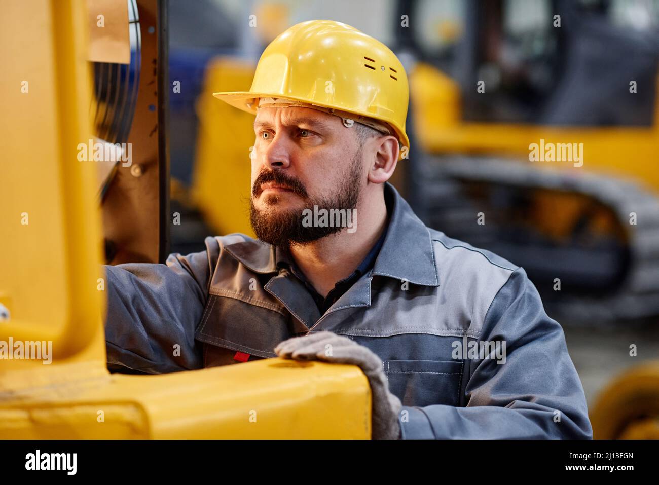 Serious foreman or repairman in boilersuit and safety helmet checking ...