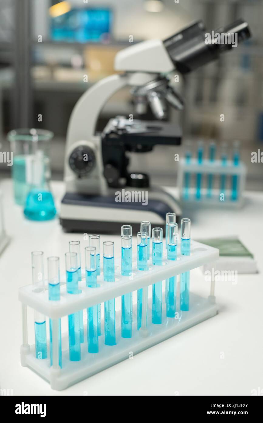 Group of flasks with samples of blue liquid standing on workplace of ...