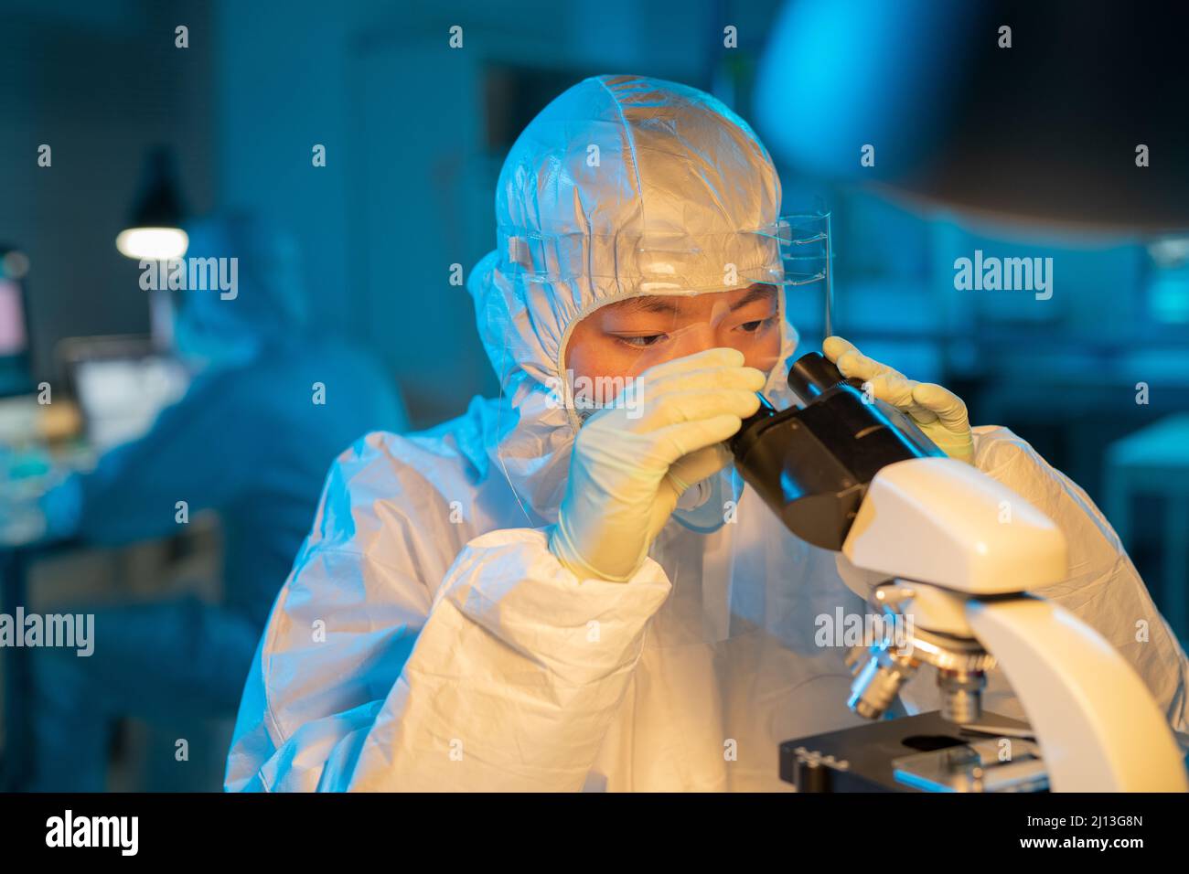 Young Asian female researcher in biohaxard suit, gloves and respirator ...