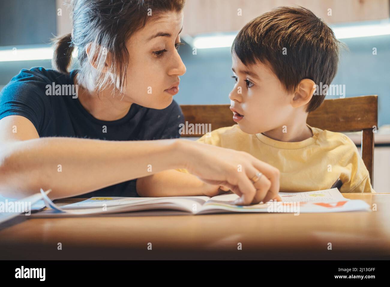 Mother correcting the error made by his son in home lessons. Studying ...