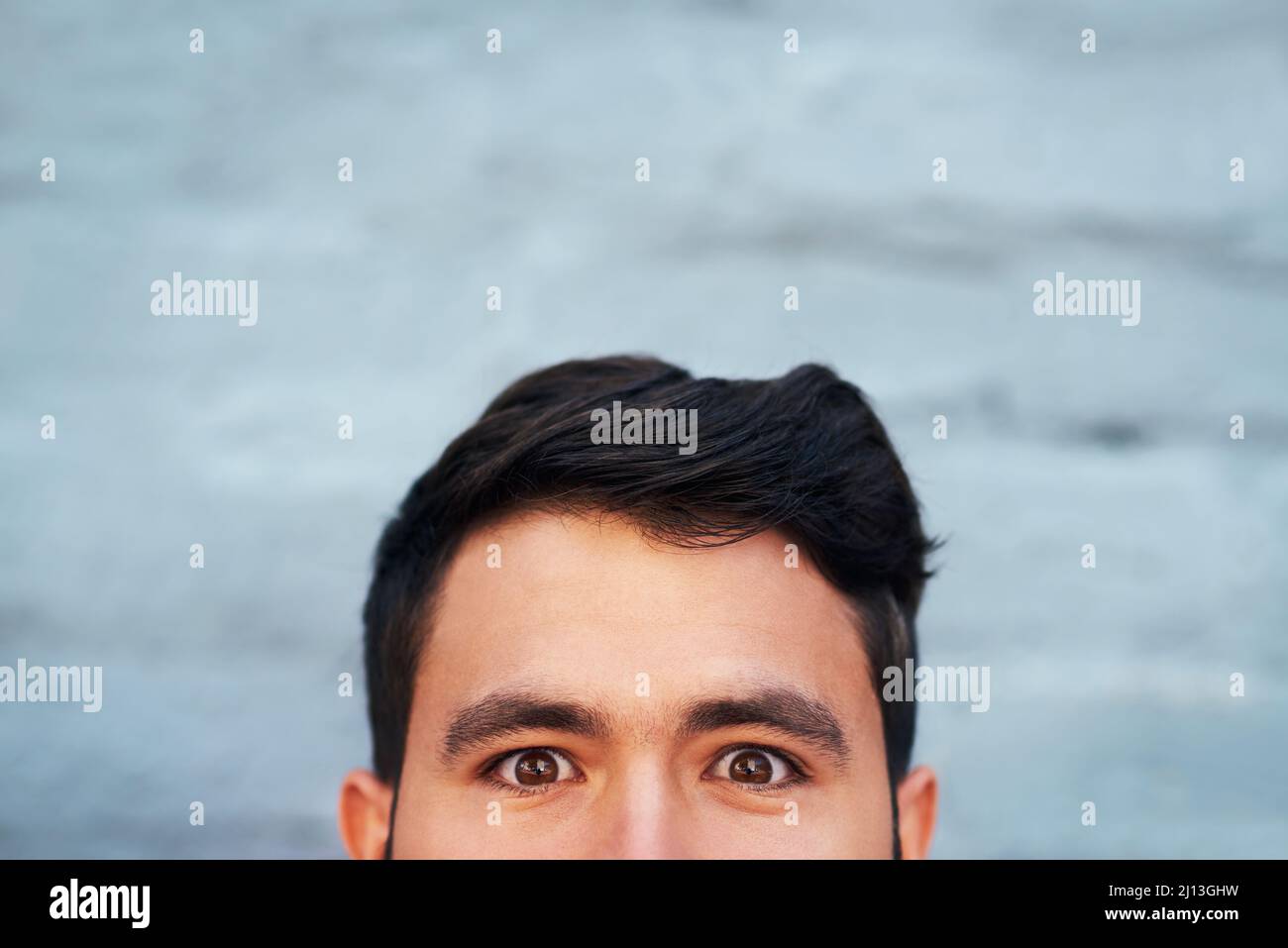 Look into my eyes. Cropped portrait of a young mans face peeking from ...