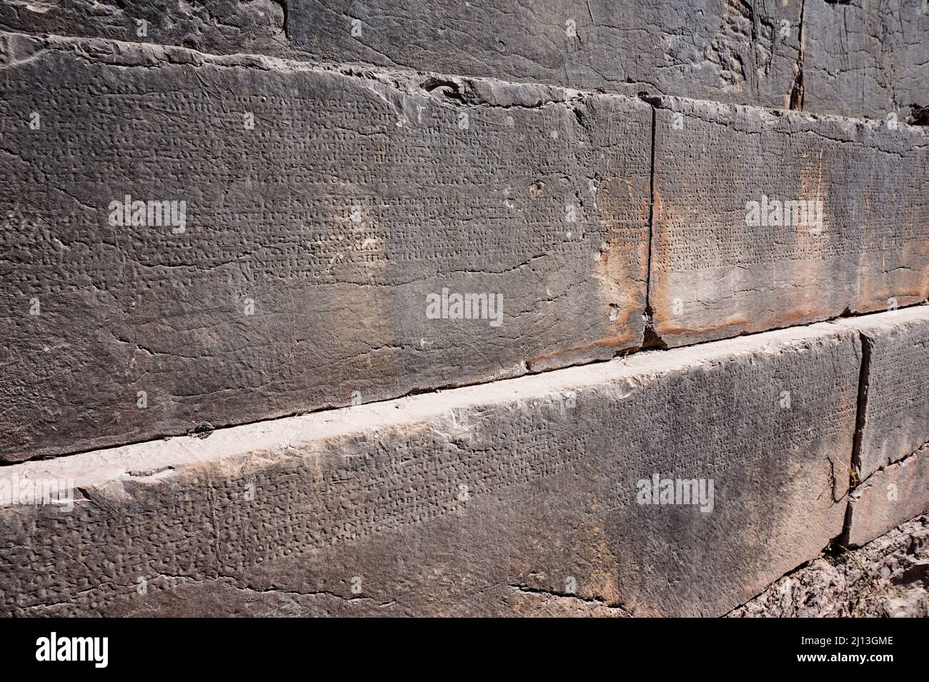 Ancient greek text on a block wall in the ruins of Delphi Stock Photo ...
