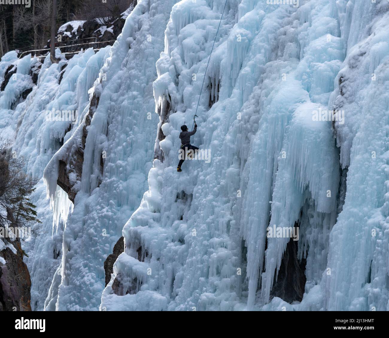 A female ice climber ascends an ice wall 160' high using ice axes and ...