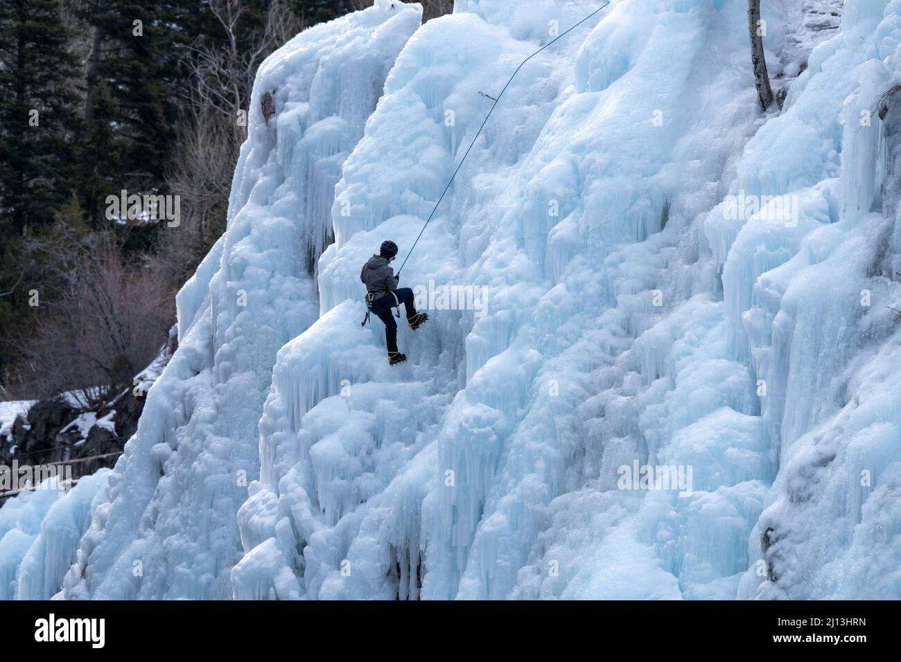 A female ice climber rappelling down an ice wall 160' high in the ...