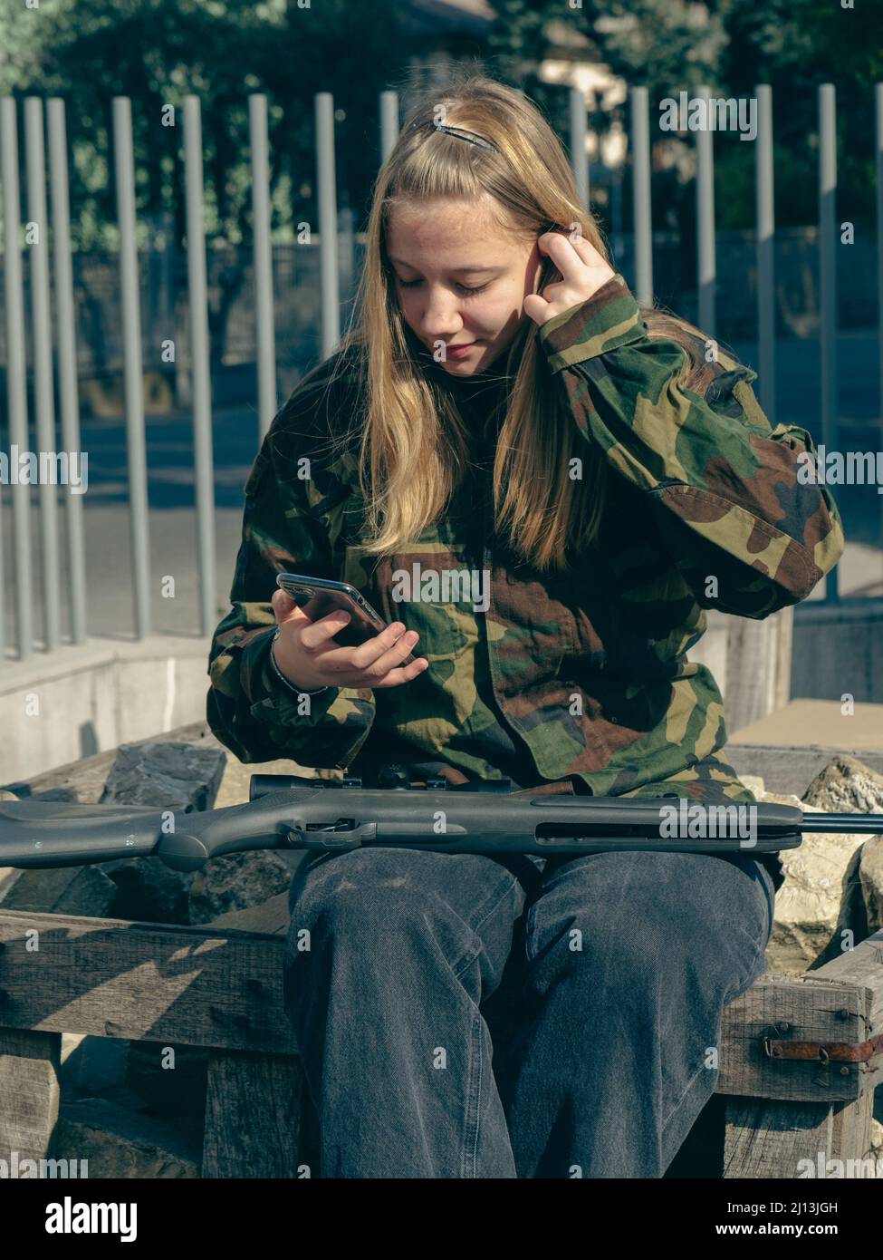 caucasian blond teen aged soldier girl using a smartphone on a ...