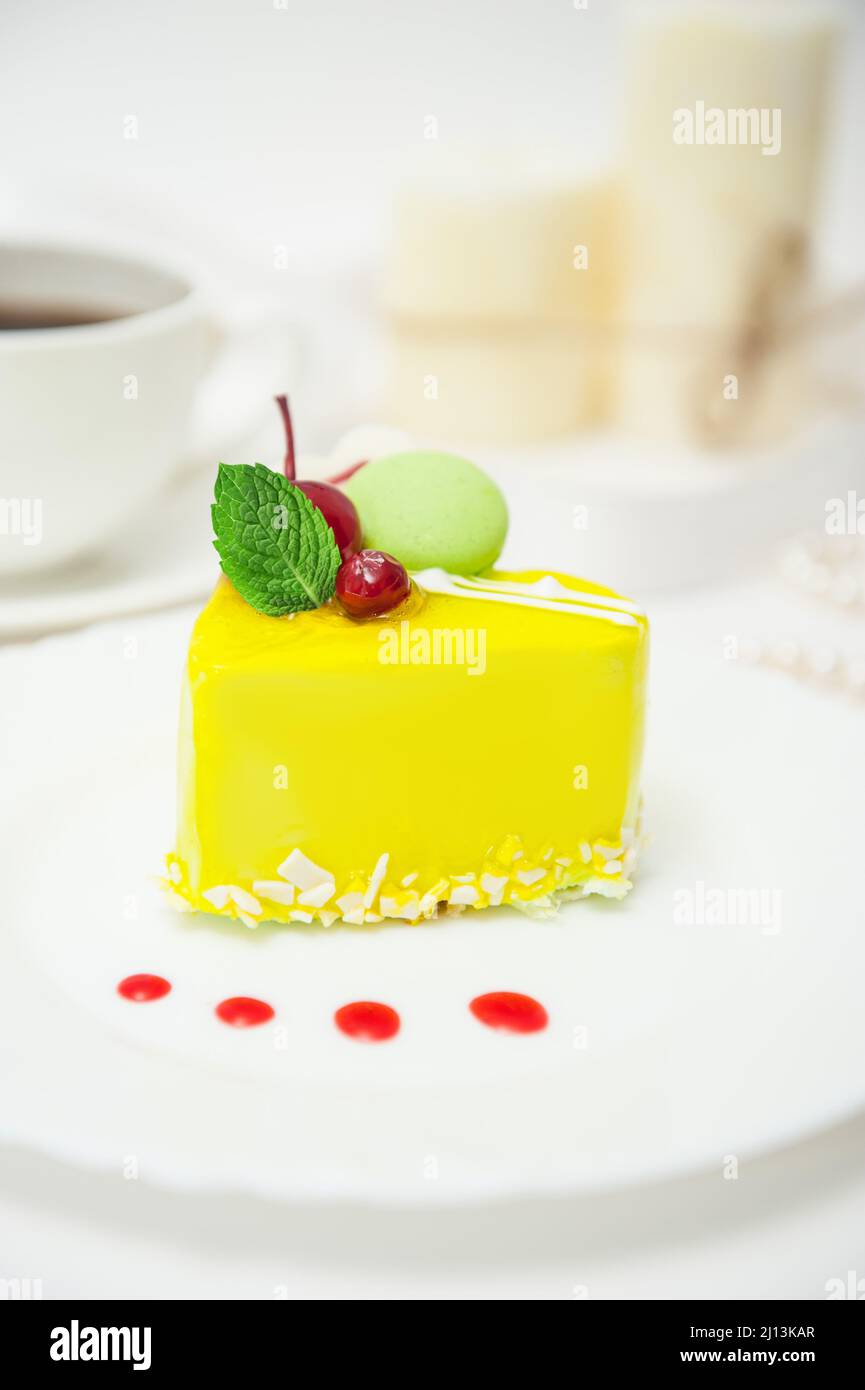 lemon yellow heart cake with cherries and cream on white background ...