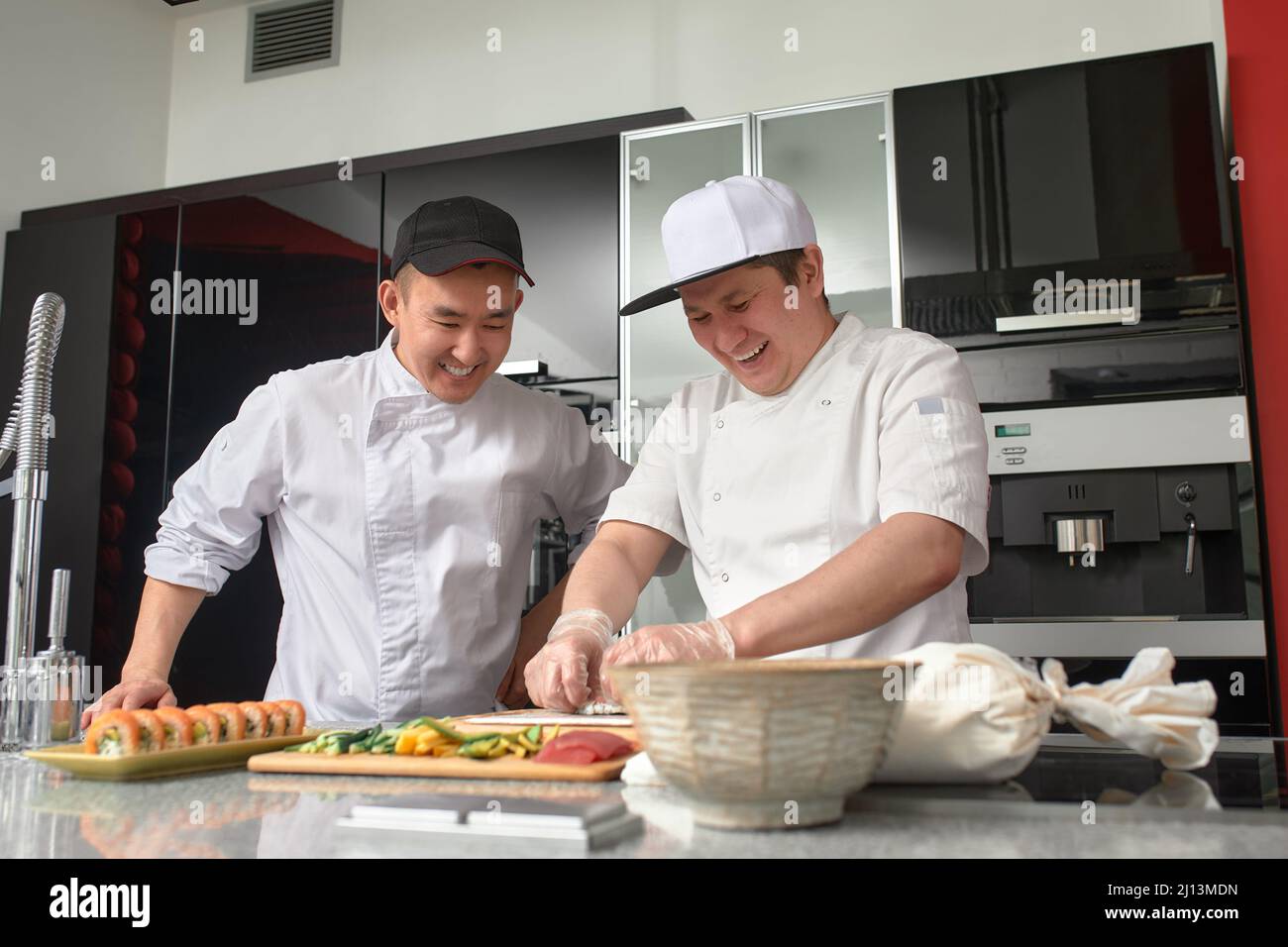 Two happy young asian chefs dressed in white uniform preparing ...