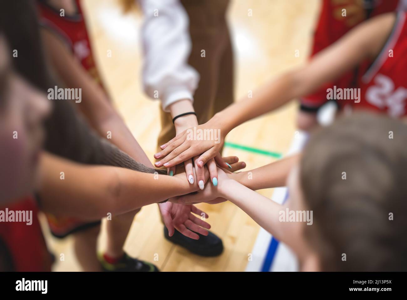 Team of kids children basketball players stacking hands in the court ...