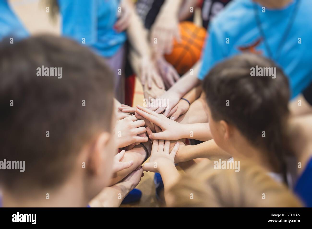 Team of kids children basketball players stacking hands in the court ...
